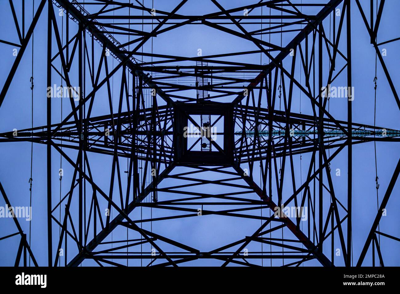 A low-angle shot from below a high-voltage electricity tower with the ...