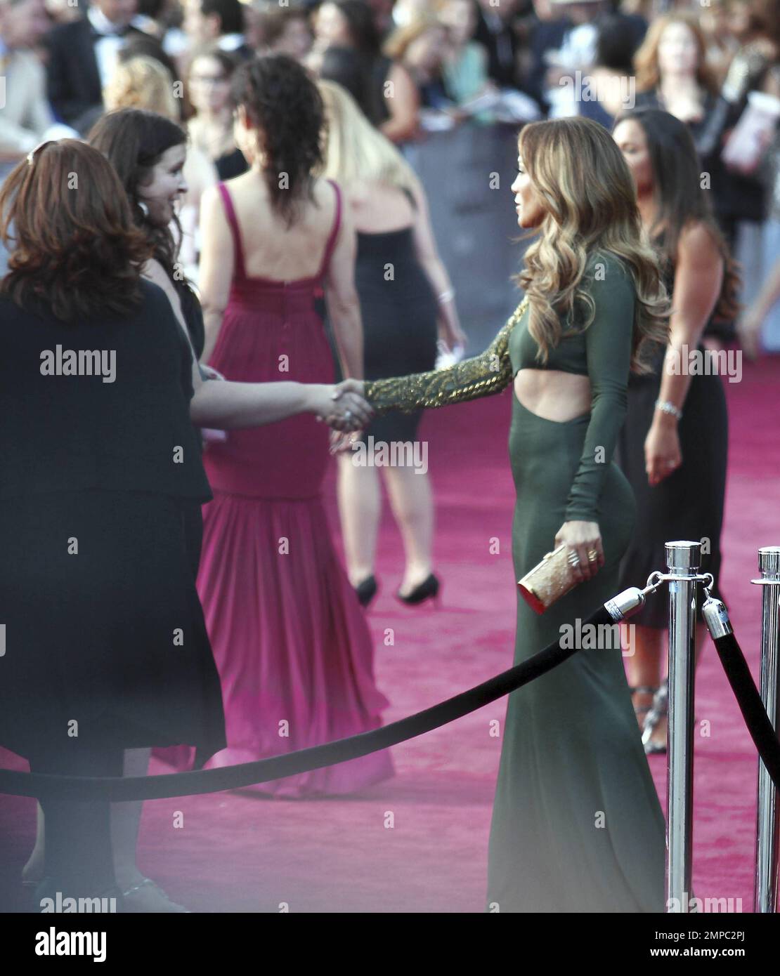 Jennifer Lopez wears a form fitting cut-away green dress as she poses ...