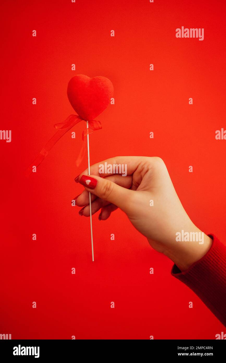 Decorative heart on a stick with ribbon in hand of the woman. Bright ...