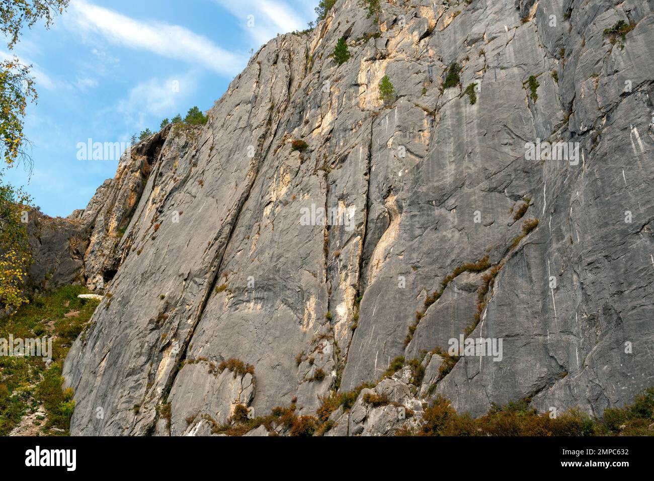 The high smooth stone wall of the mountain goes into the sky with ...
