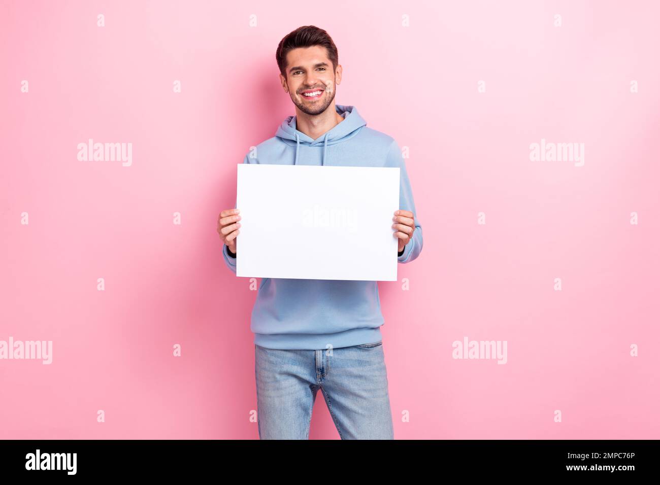 Photo of cheerful positive man wear blue hoodie holding white placard ...