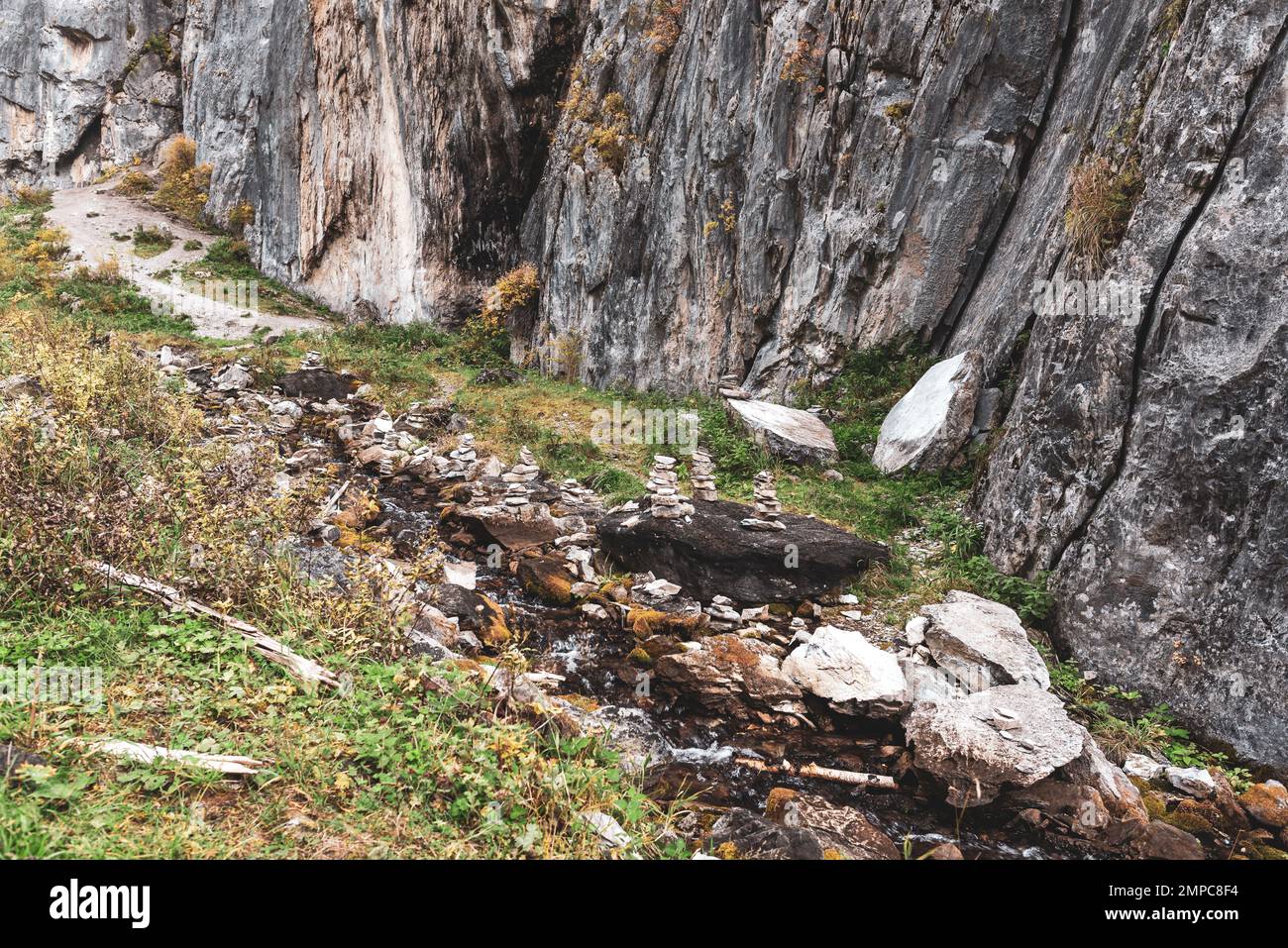The trail goes along the stone wall of the mountain. An ancient man's ...