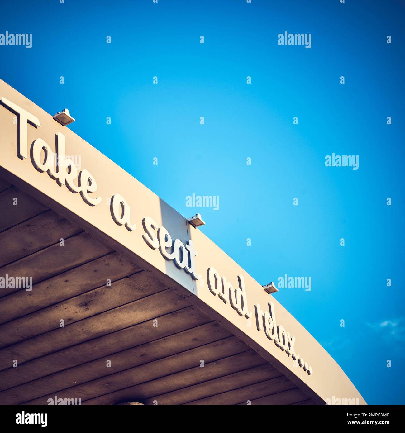 Take a seat and relax sign above cafe entrance Stock Photo - Alamy