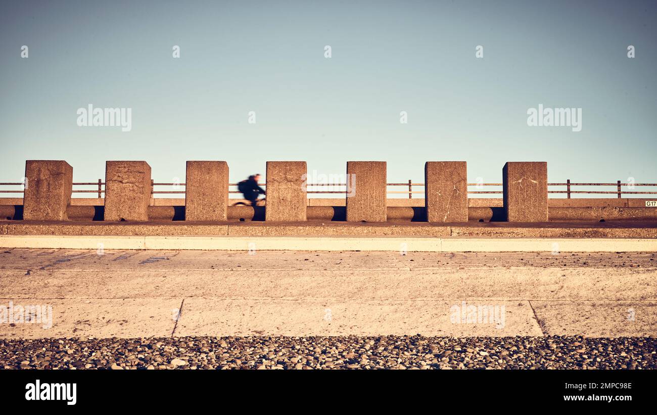 Cycling past concrete columns on Rossall seawall Stock Photo - Alamy
