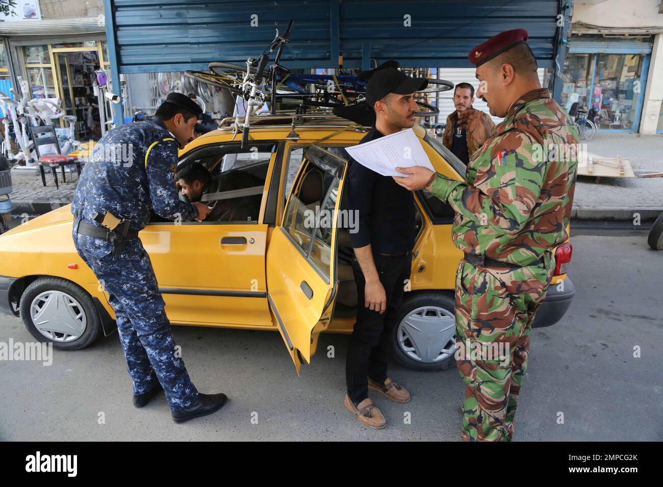 Members of Iraq security forces search cars and check documents at a ...
