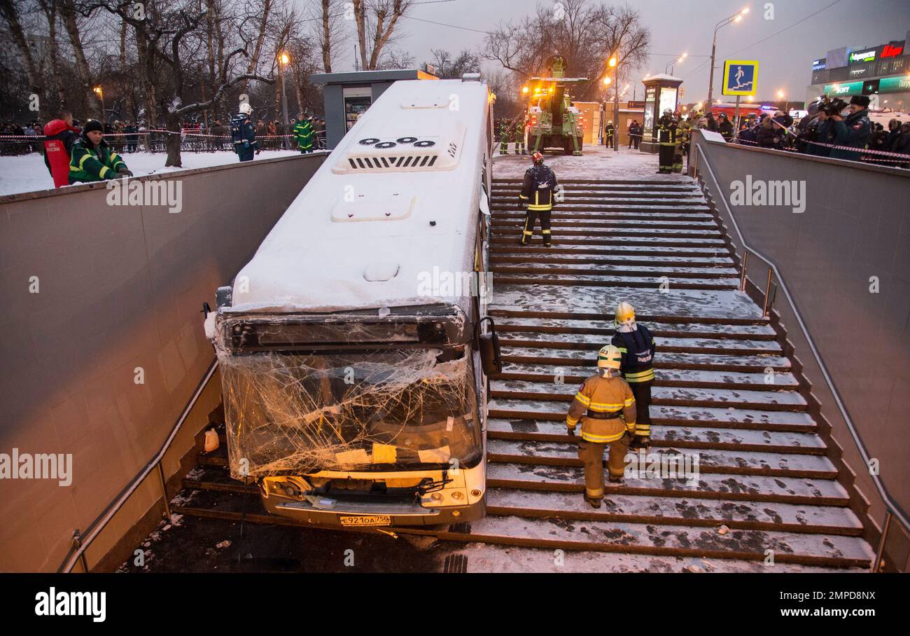 Emergency personnel work to pull a bus that crashed out from a subway ...