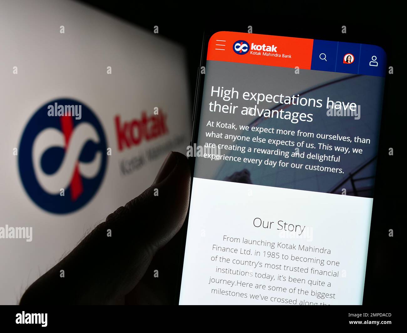 Person holding cellphone with webpage of Indian financial company Kotak ...