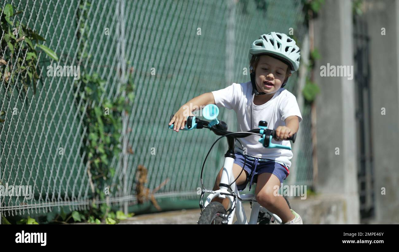Happy child rides bicycle wearing helmet. Cyclist kid rides bike in ...