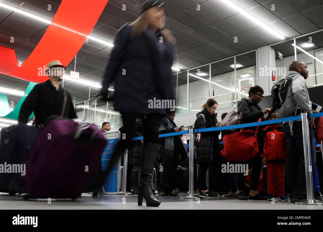 Travelers line up at a security checkpoint area and walk in Terminal 3 ...