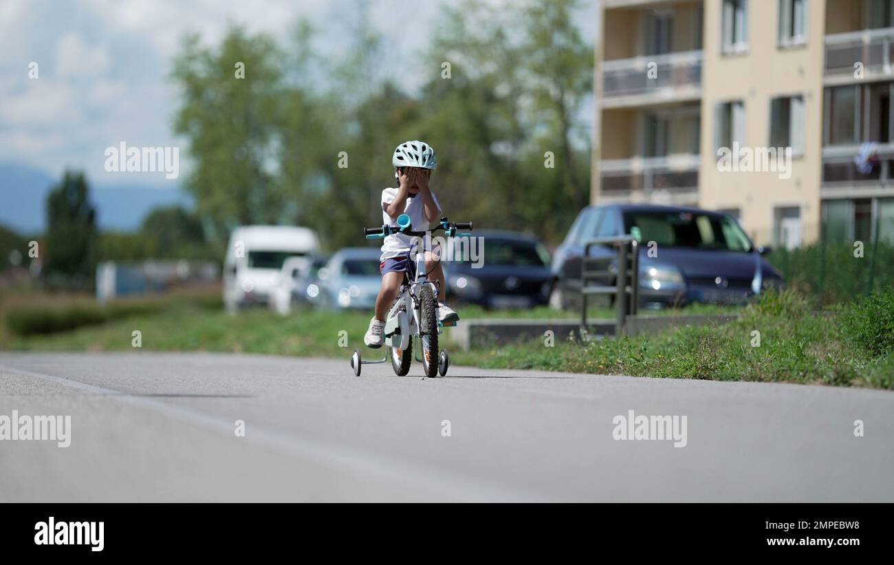 One tearful cyclist child covering face feeling sad. Small boy wearing ...
