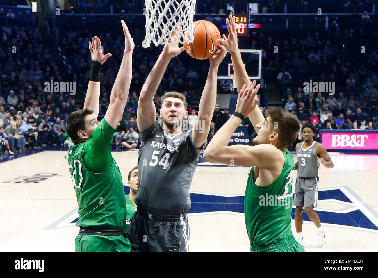 Xavier's Sean O'Mara (54) shoots against Marshall's Milan Mijovic, left ...