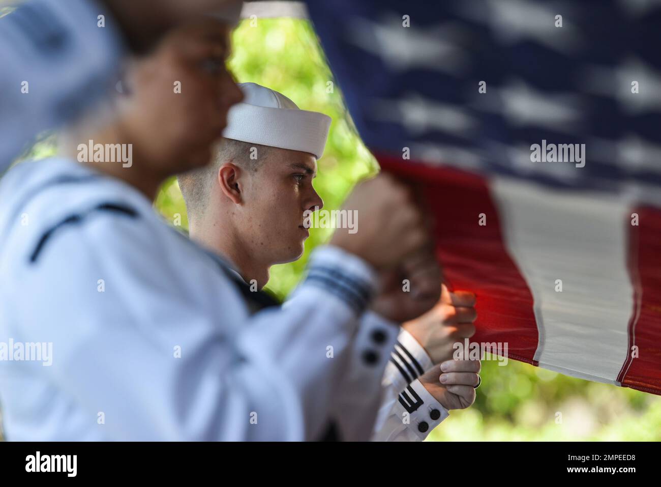 U.S. Navy Sailors assigned to Navy Region Hawaii hold a U.S. flag ...