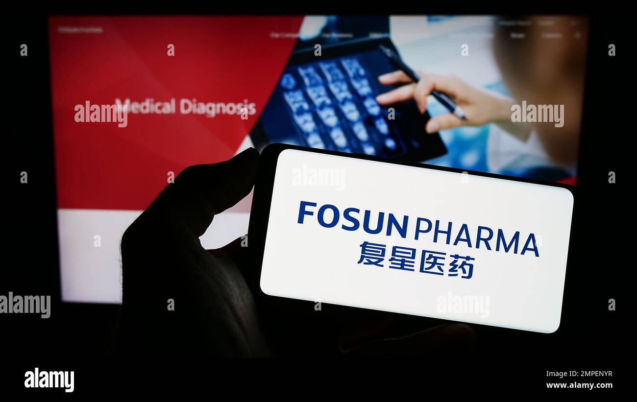 Person holding cellphone with logo of Chinese pharmaceutical company Fosun Pharma on screen in ...
