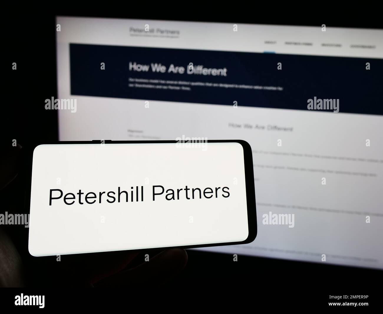 Person holding mobile phone with logo of investment company Petershill ...