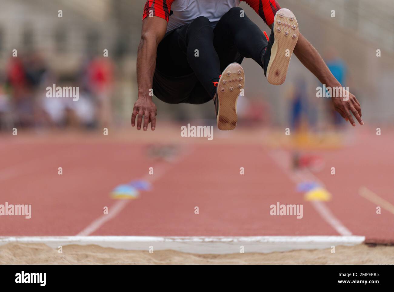 Athlete in long jump during competition, performing triple long jump on ...