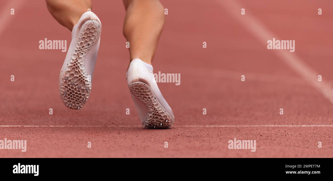 Female athlete running on stadium track, dynamic run of sprinter in a ...