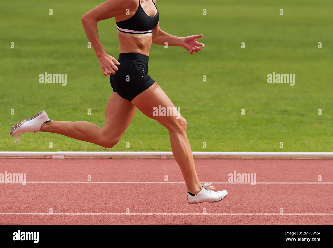 Female athlete running on stadium track, dynamic run of sprinter in a ...