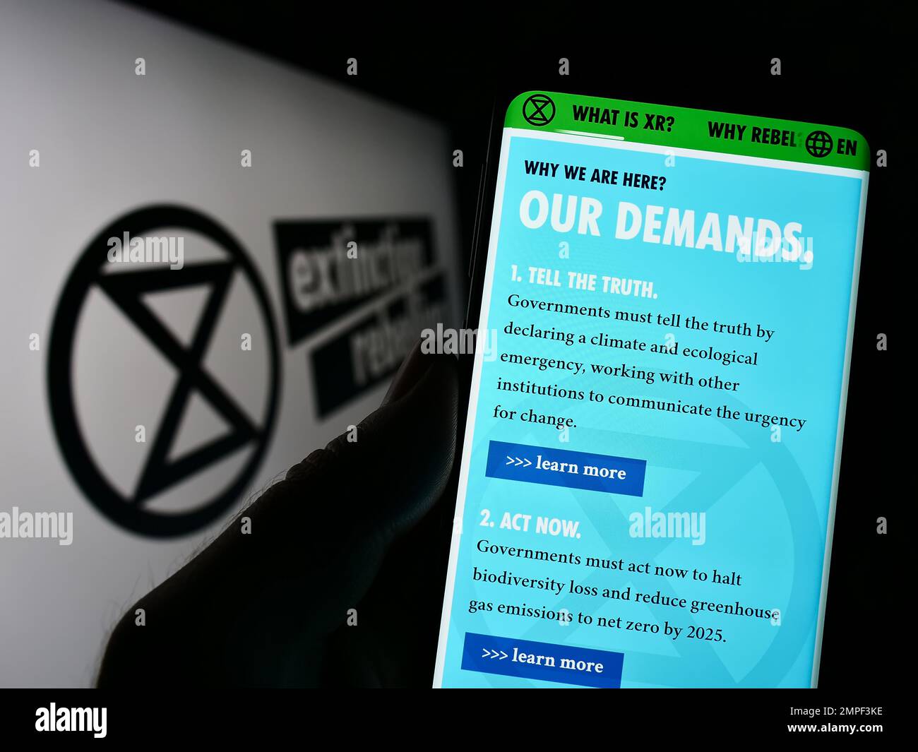 Person holding cellphone with web page of organization Extinction ...