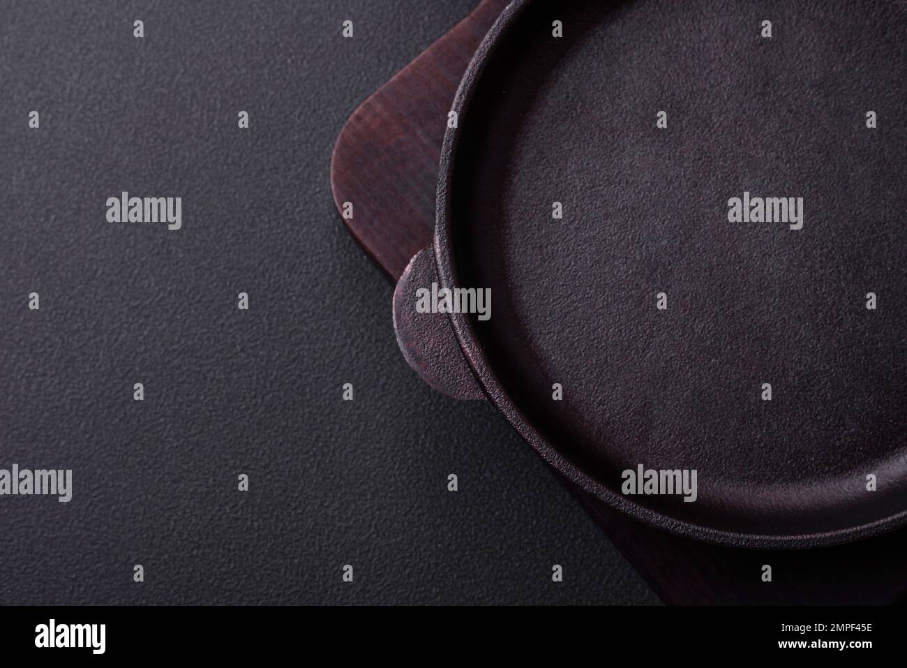 Empty round cast iron skillet on dark textured concrete background ...