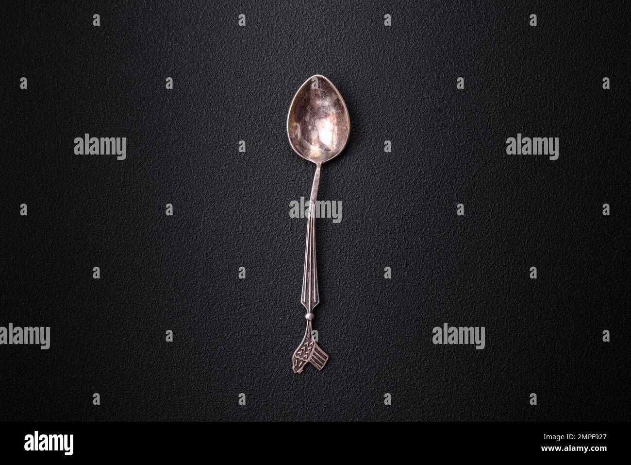 Empty metal spoon on dark textured concrete background. Cutlery ...
