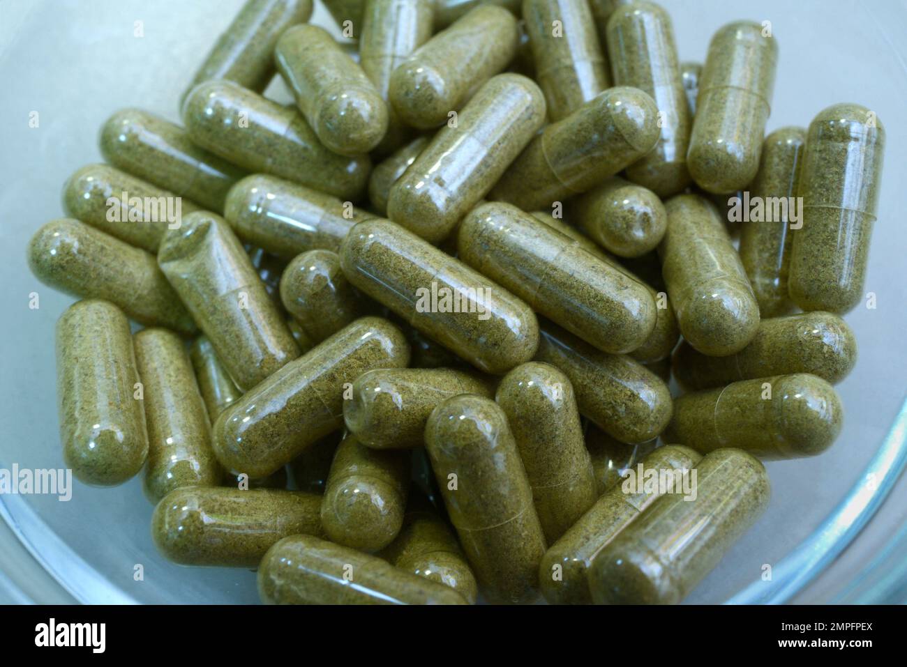 Capsules with green stuff inside put on a glass plate Stock Photo - Alamy