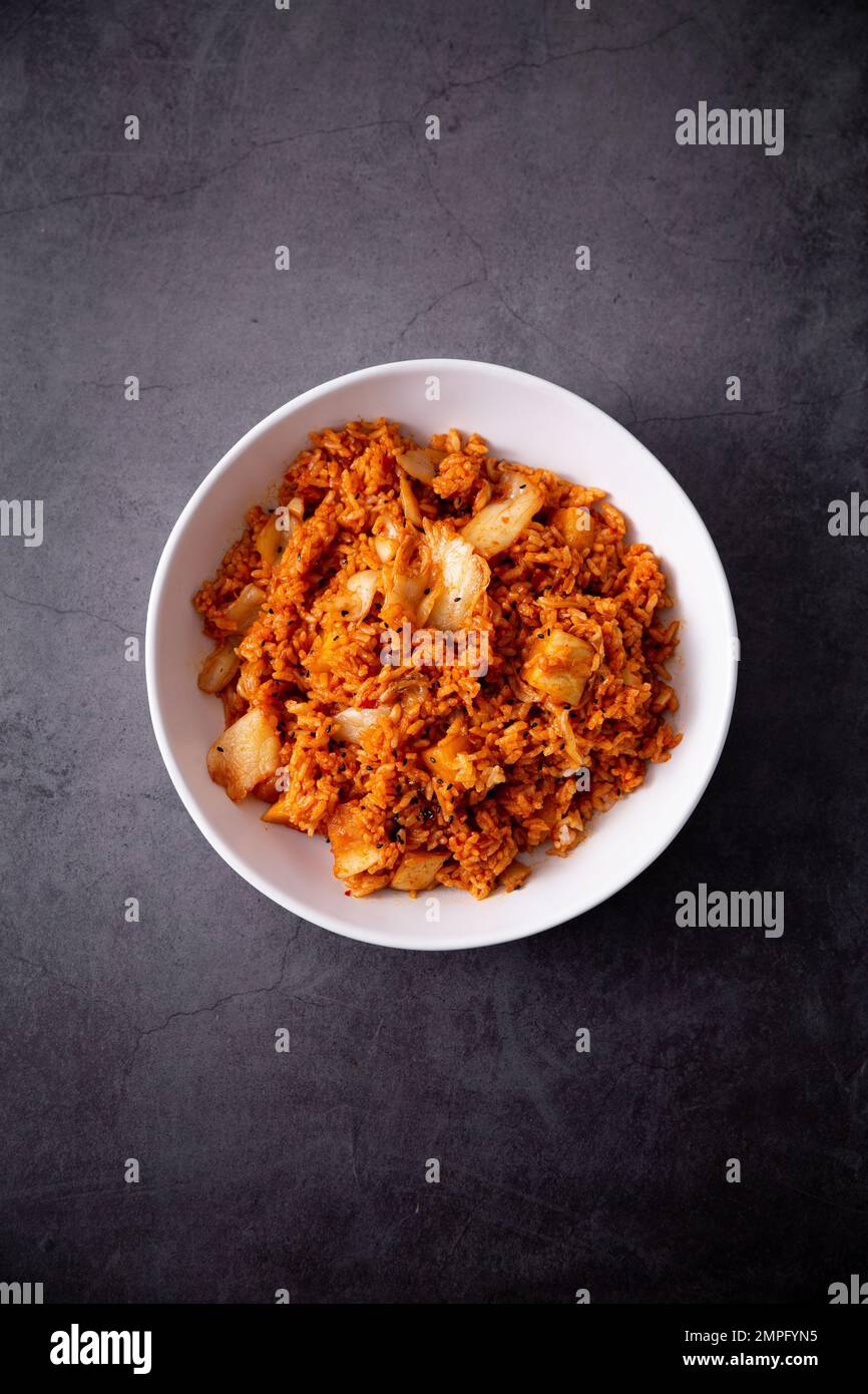 A vertical top view of a Korean kimchi in a white bowl on a gray table ...