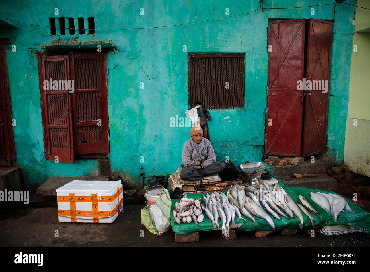 A fish vendor waits for customers at his roadside stall in Lucknow, in ...