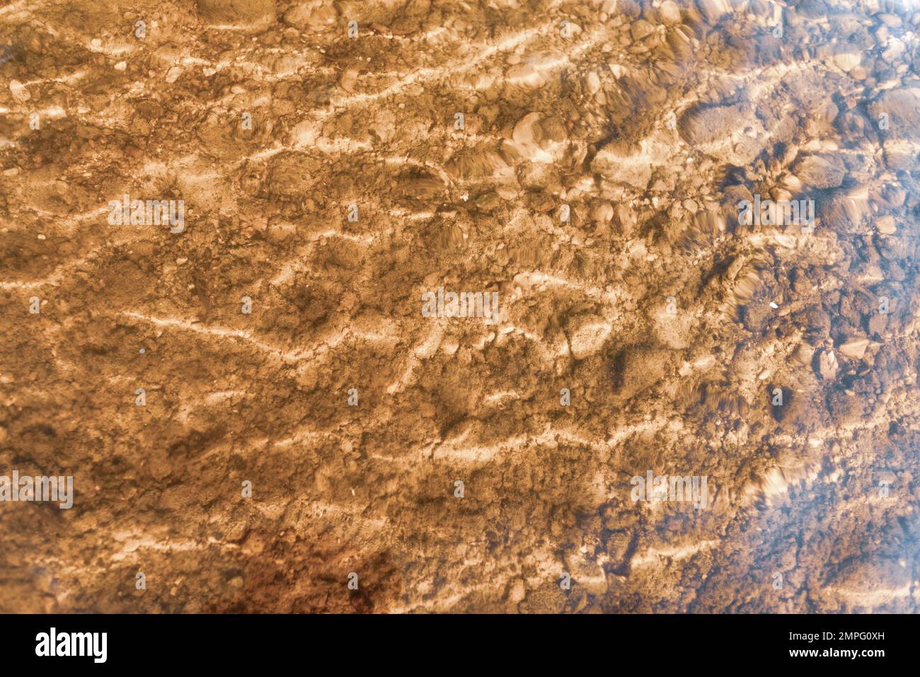 The bottom of the river through clear water with the reflection of the ...