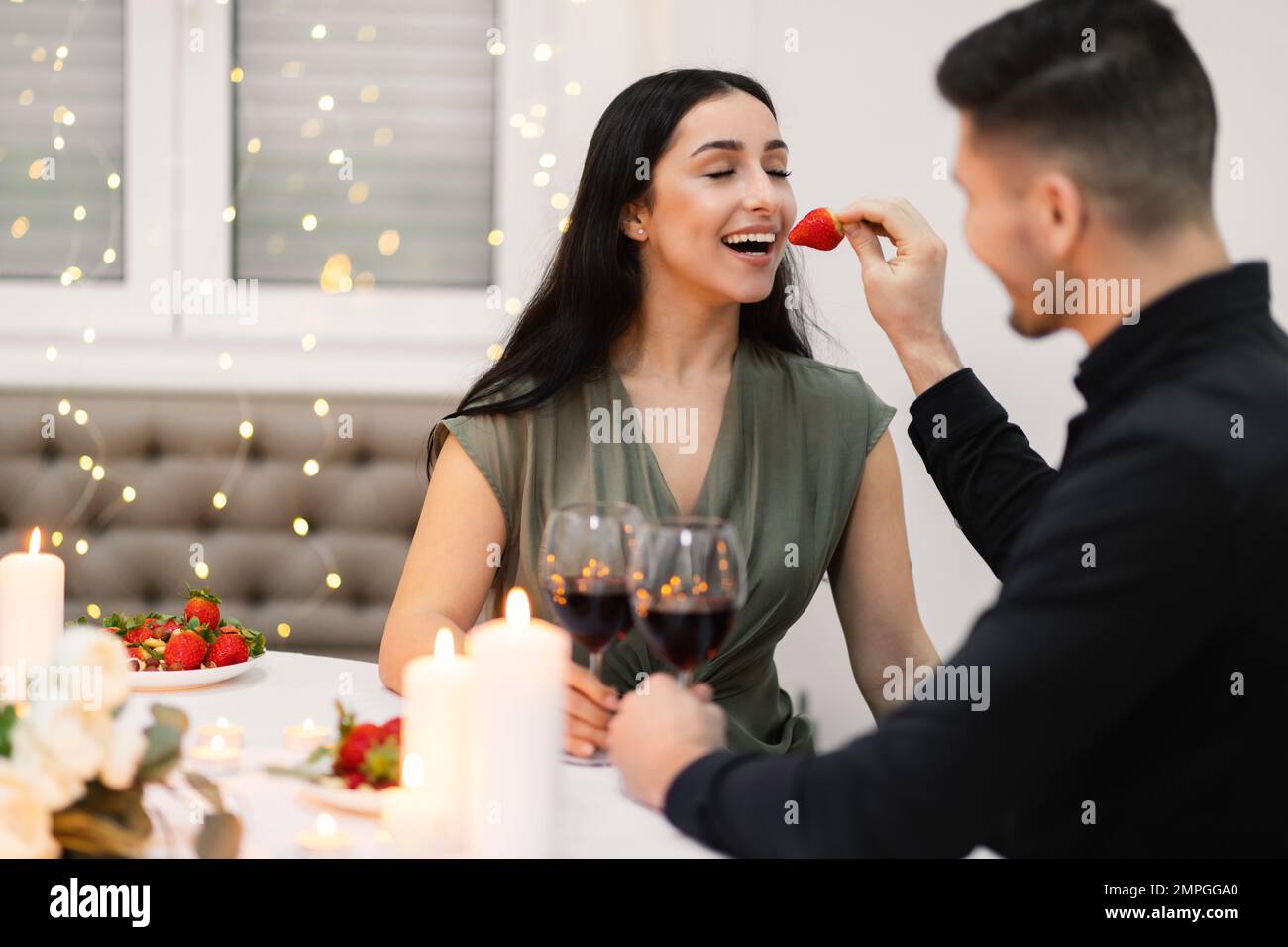 Beautiful young couple celebrating anniversary at home, eating ...