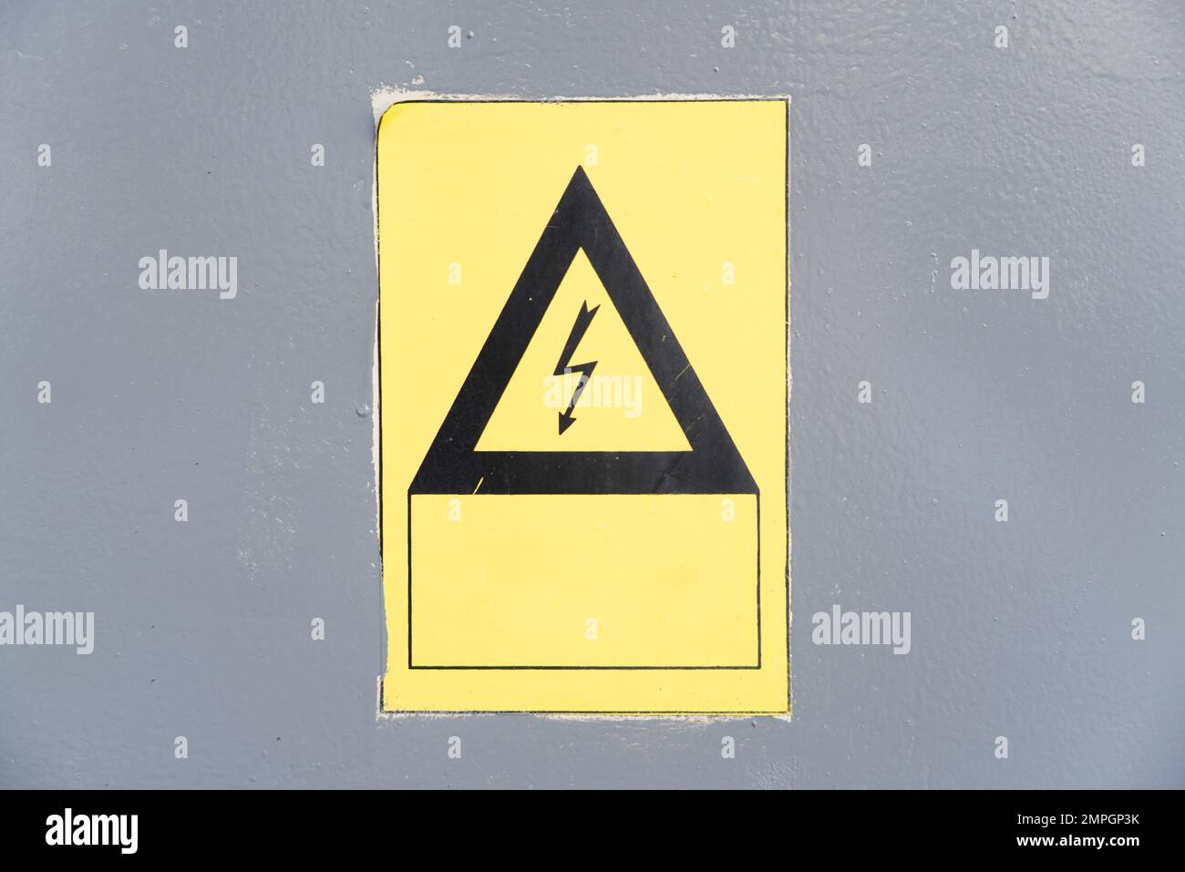 Close-up of warning yellow sign for electricity isolated on grey ...