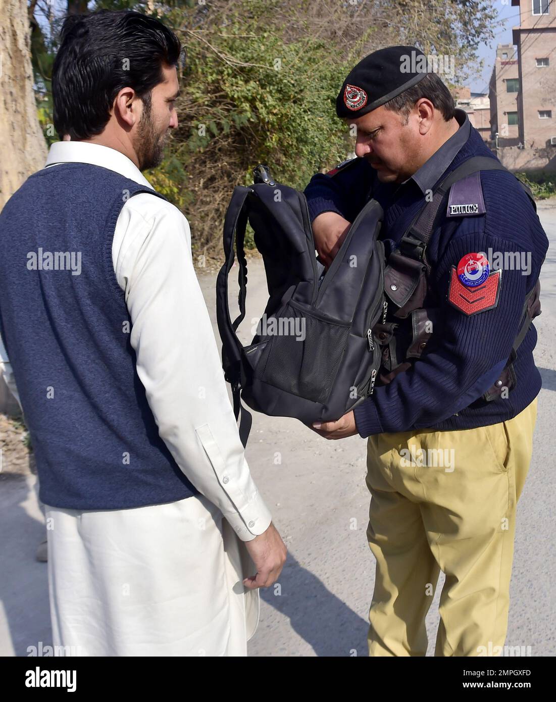 Peshawar. 31st Jan, 2023. A policeman checks a man's backpack under ...