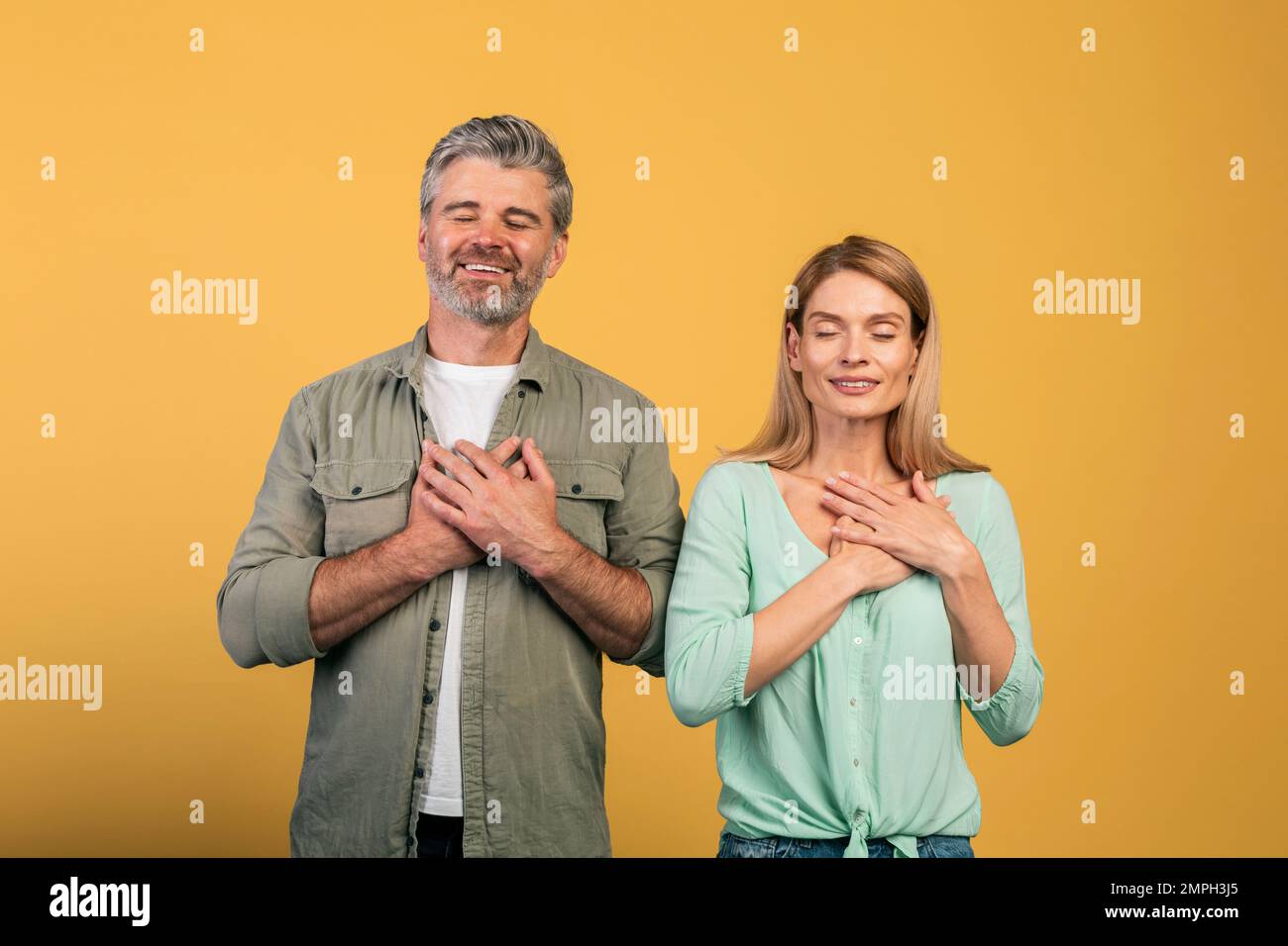 Thank you. Grateful middle aged couple with closed eyes keeping both ...