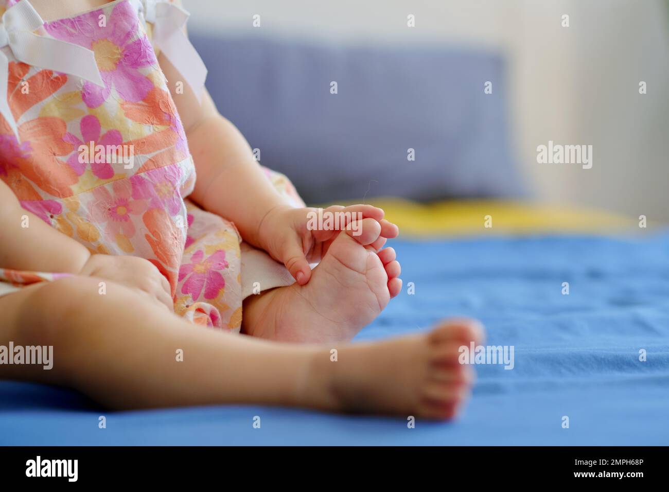 Cropped image of little girl touching her feet when playing on bed of ...