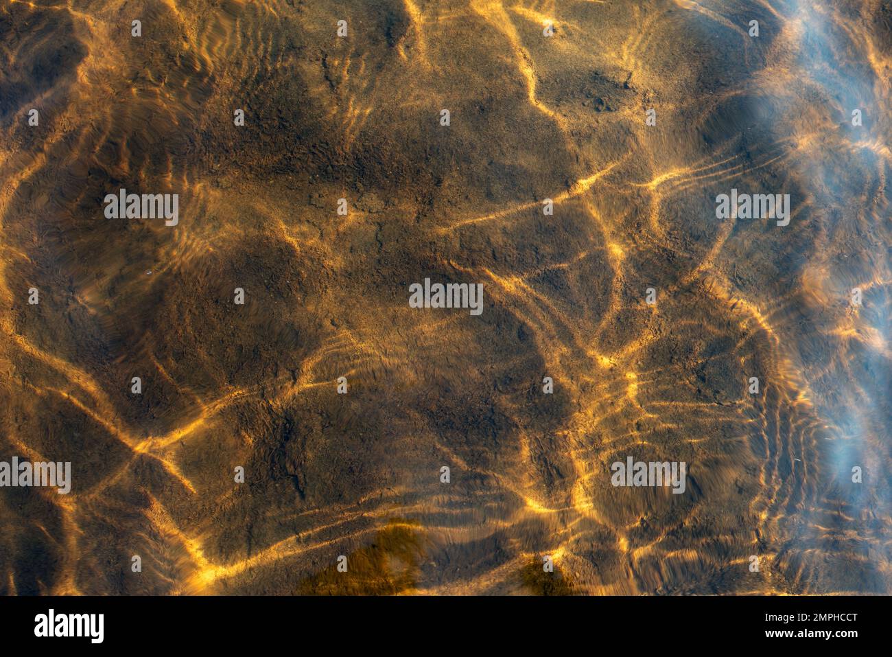 Reflection of sunlight from the waves of transparent water with a sandy ...