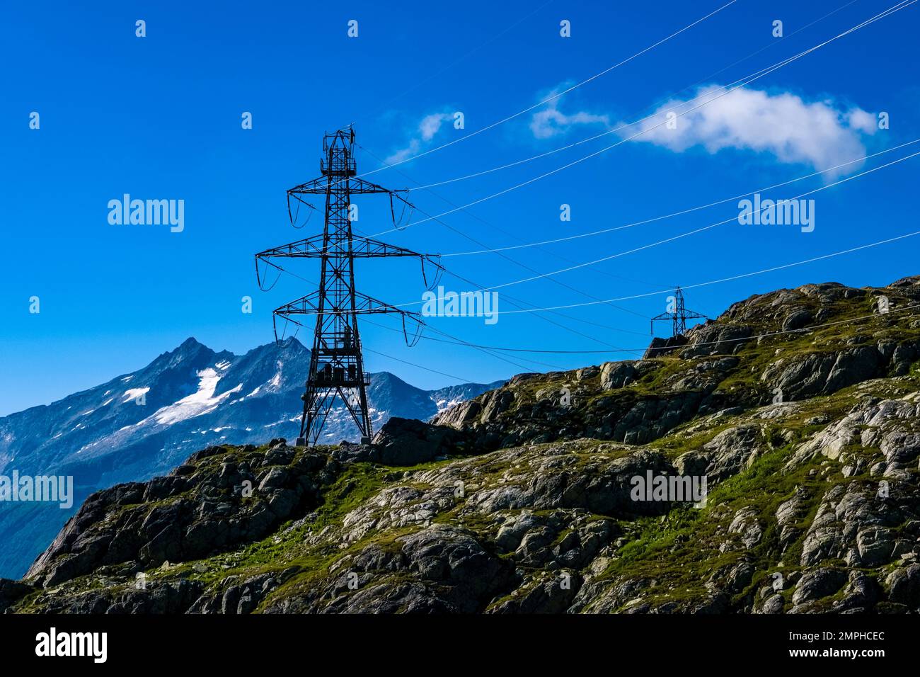 High voltage pylons are set on rocky landscape around the mountain pass ...