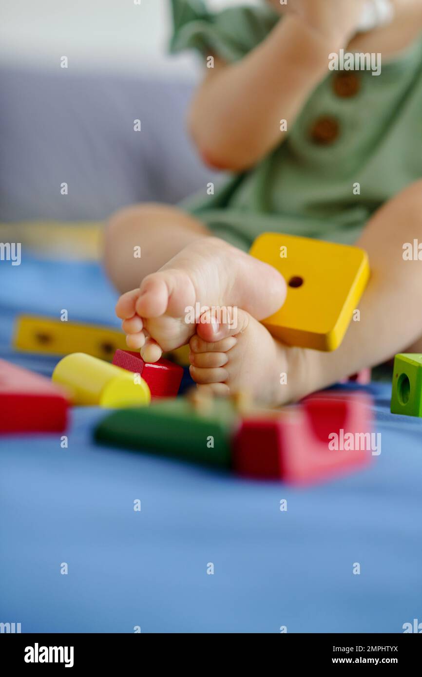 Feet of little girl playing with colorful wooden bricks Stock Photo - Alamy