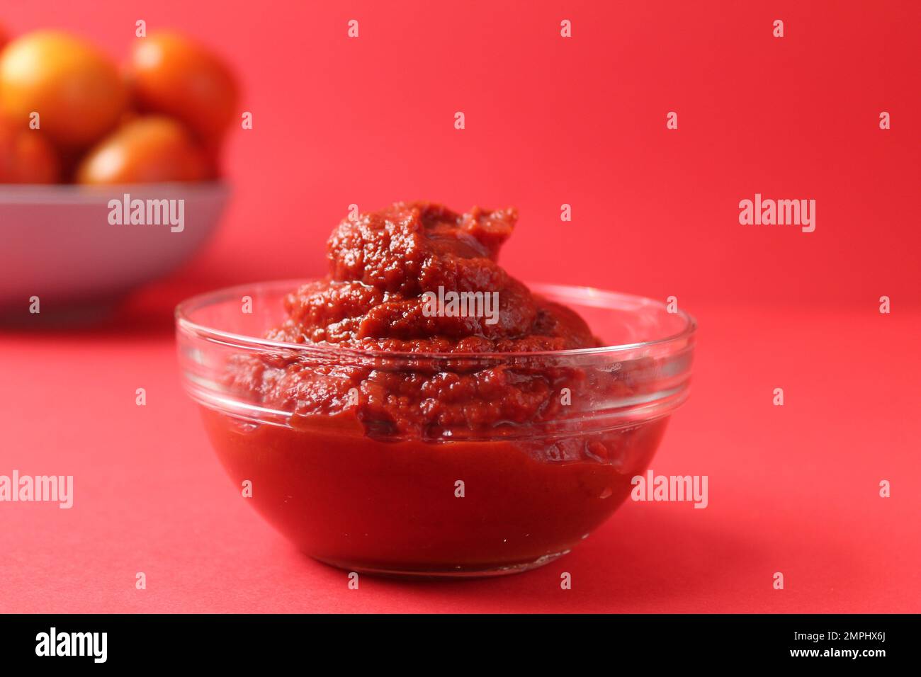 tomato paste in a glass sauce bowl on a red background monocolor. Food ...
