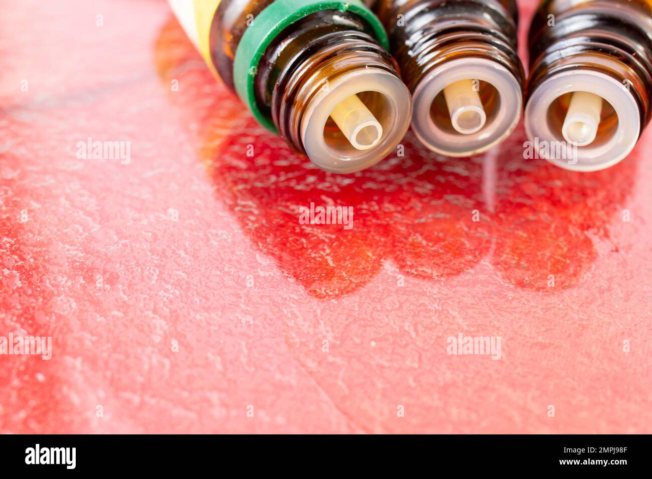 Three essential oil bottles on red corrugated glass, soft focus ...