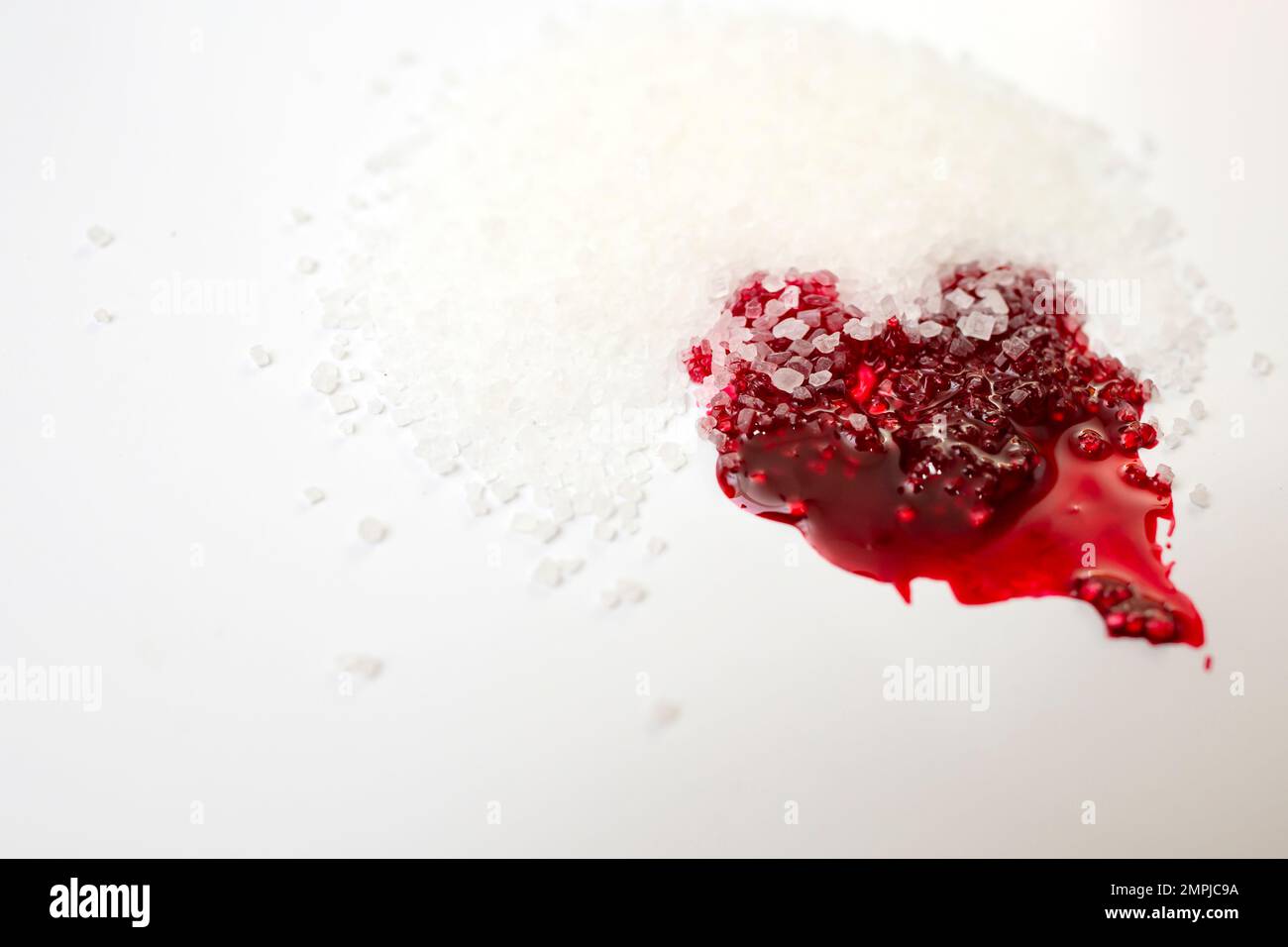 Red blood splatter mixed with sugar crystals on white background, soft ...