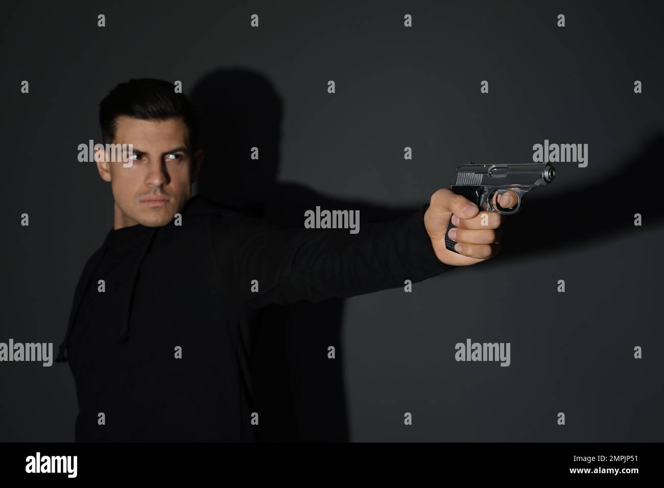 Professional killer with gun on black background Stock Photo - Alamy