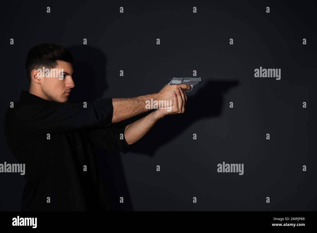 Professional killer with gun on black background Stock Photo - Alamy