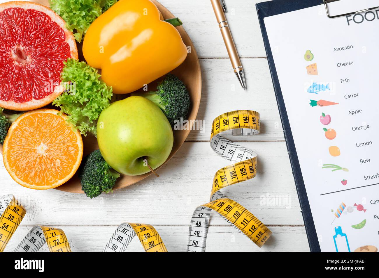 Fruits, vegetables, measuring tape and list of products on white wooden ...