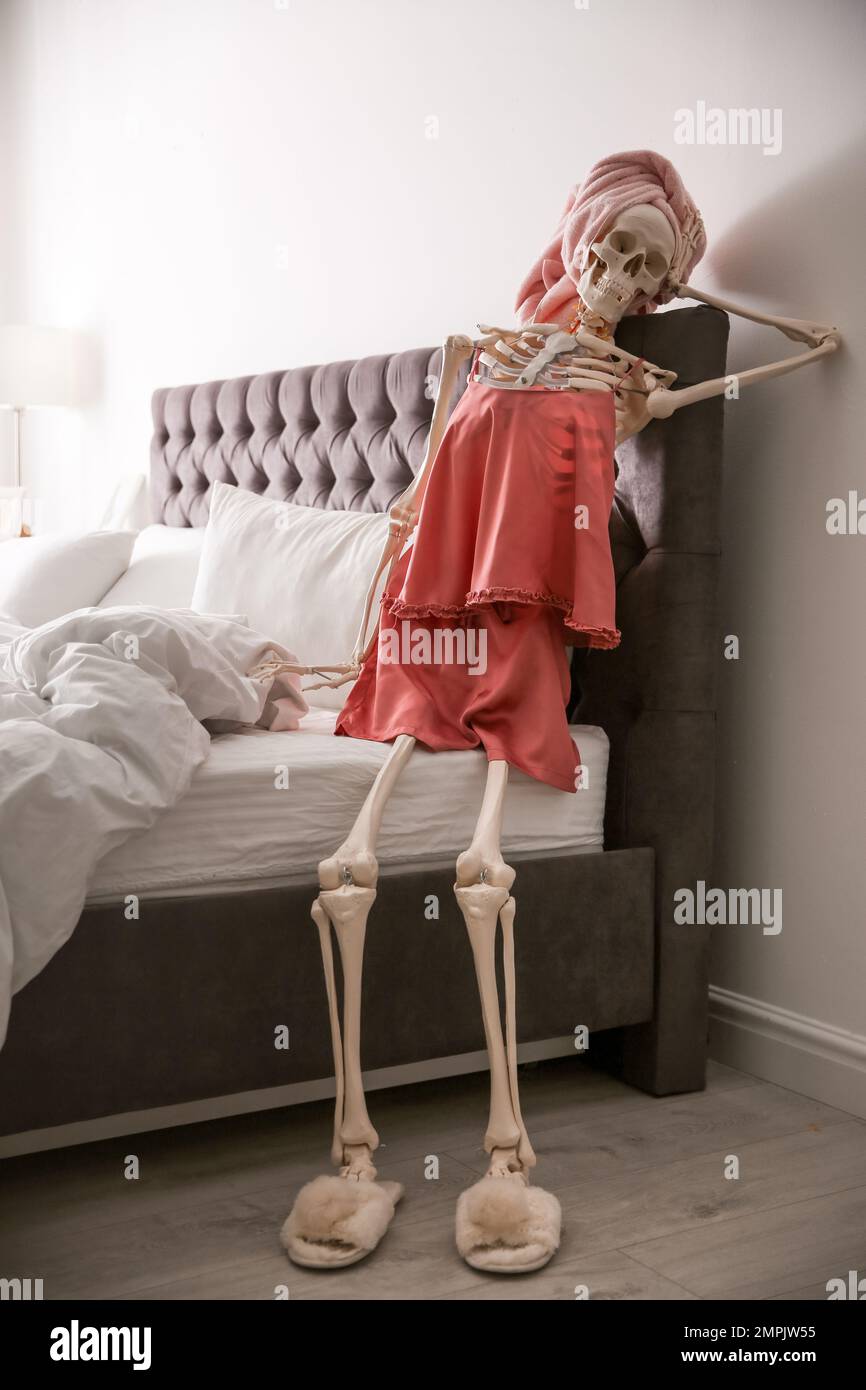 Human skeleton in silk pajamas and towel sitting on bed indoors Stock ...