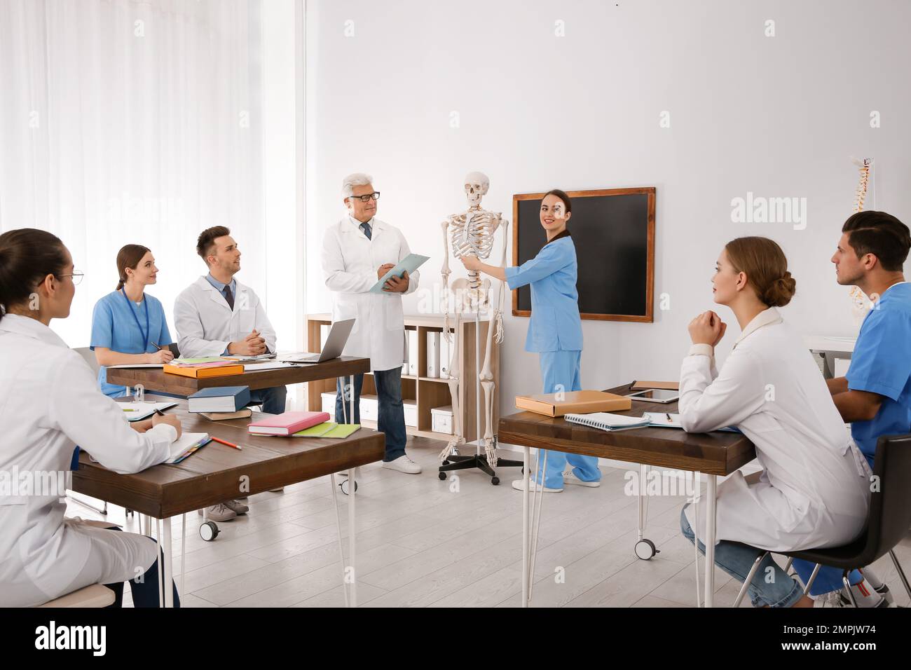 Medical students and professor studying human skeleton anatomy in ...