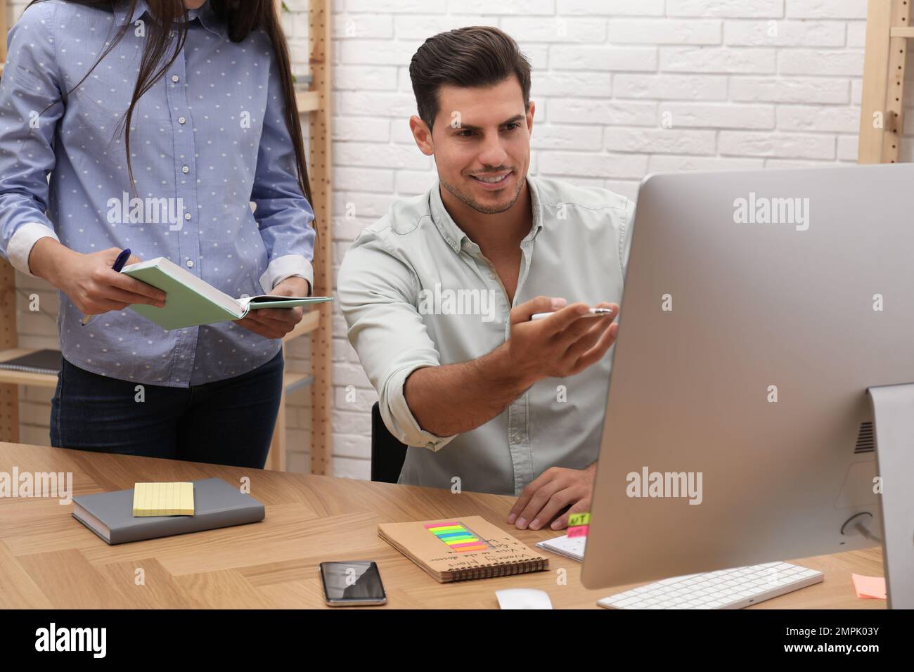 Colleagues making schedule using calendar in office Stock Photo - Alamy