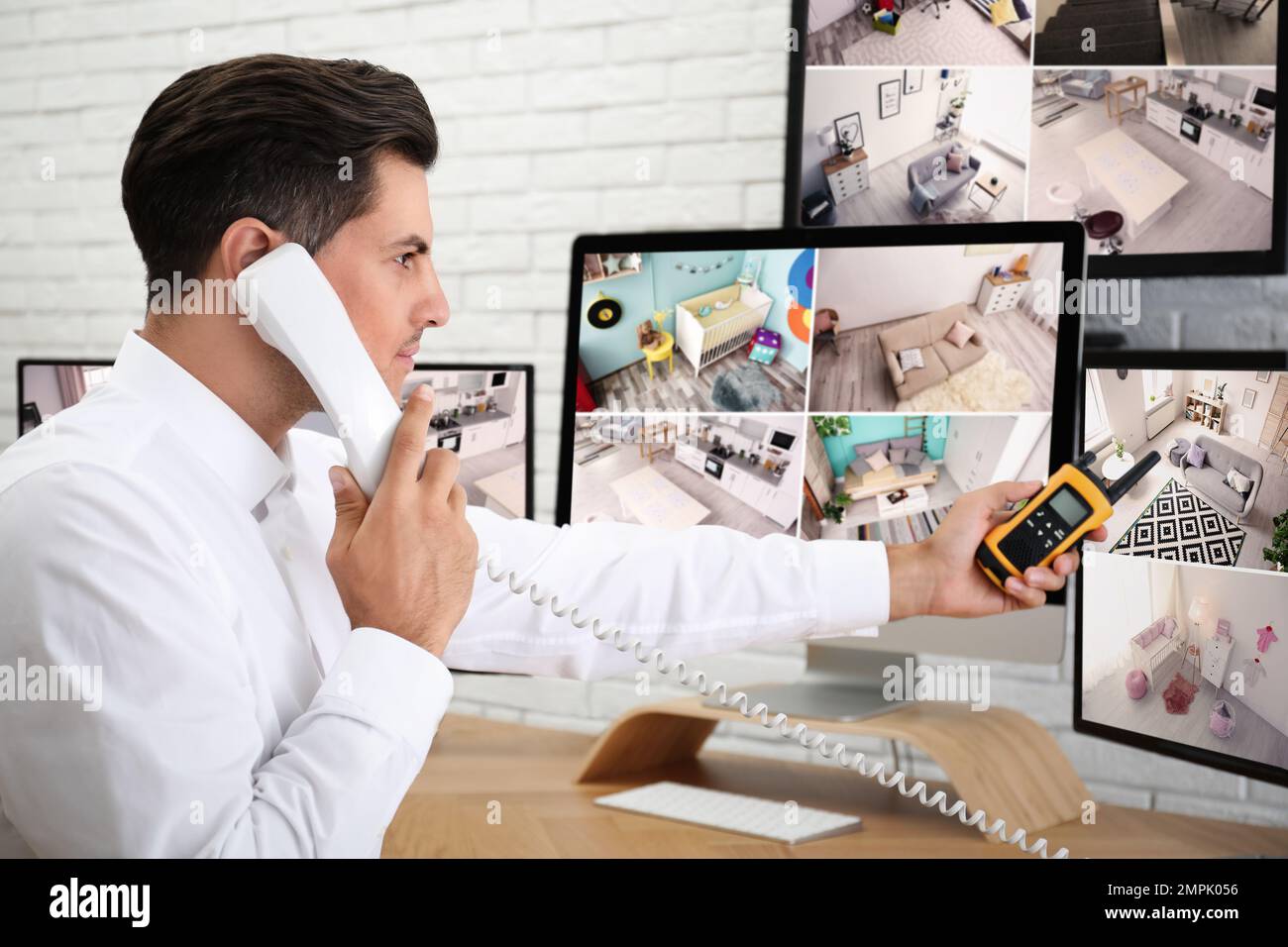 Male security guard talking by telephone near monitors at workplace ...