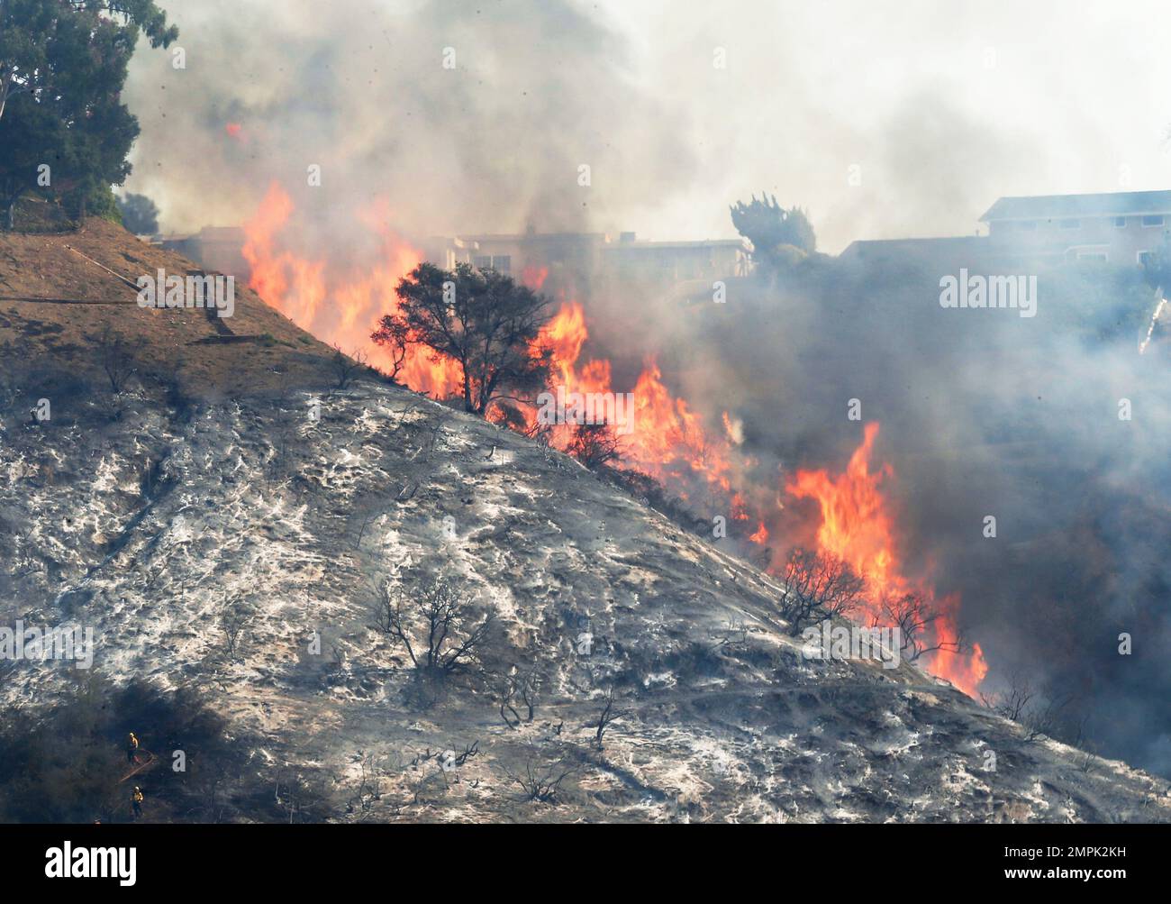 Flames sweep up a steep canyon wall, threatening homes on a ridge line ...