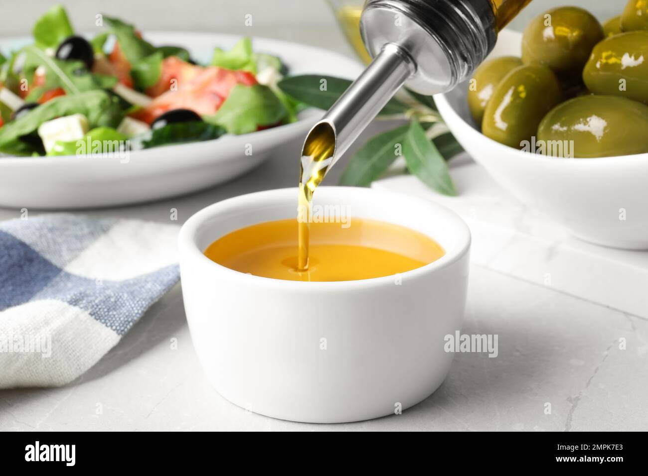 Pouring cooking oil into bowl on light grey marble table Stock Photo ...