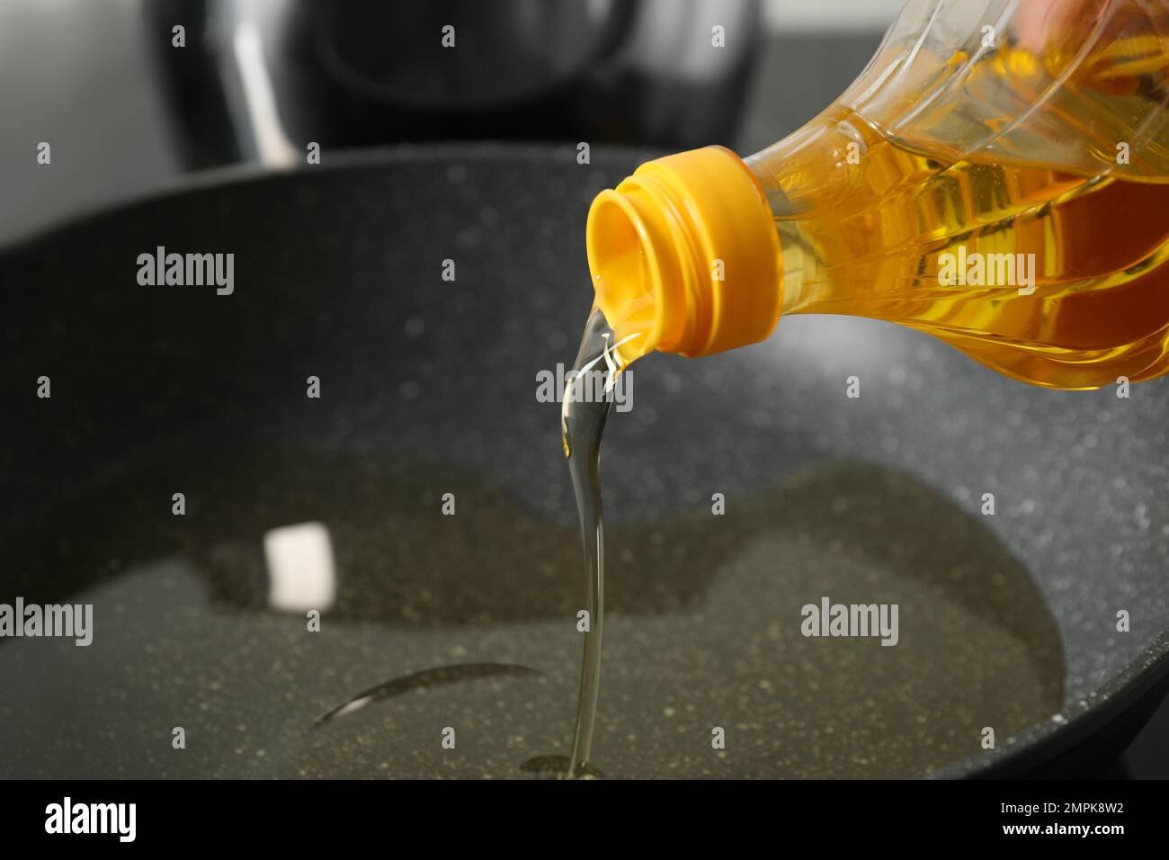 Pouring cooking oil from bottle into frying pan, closeup Stock Photo ...