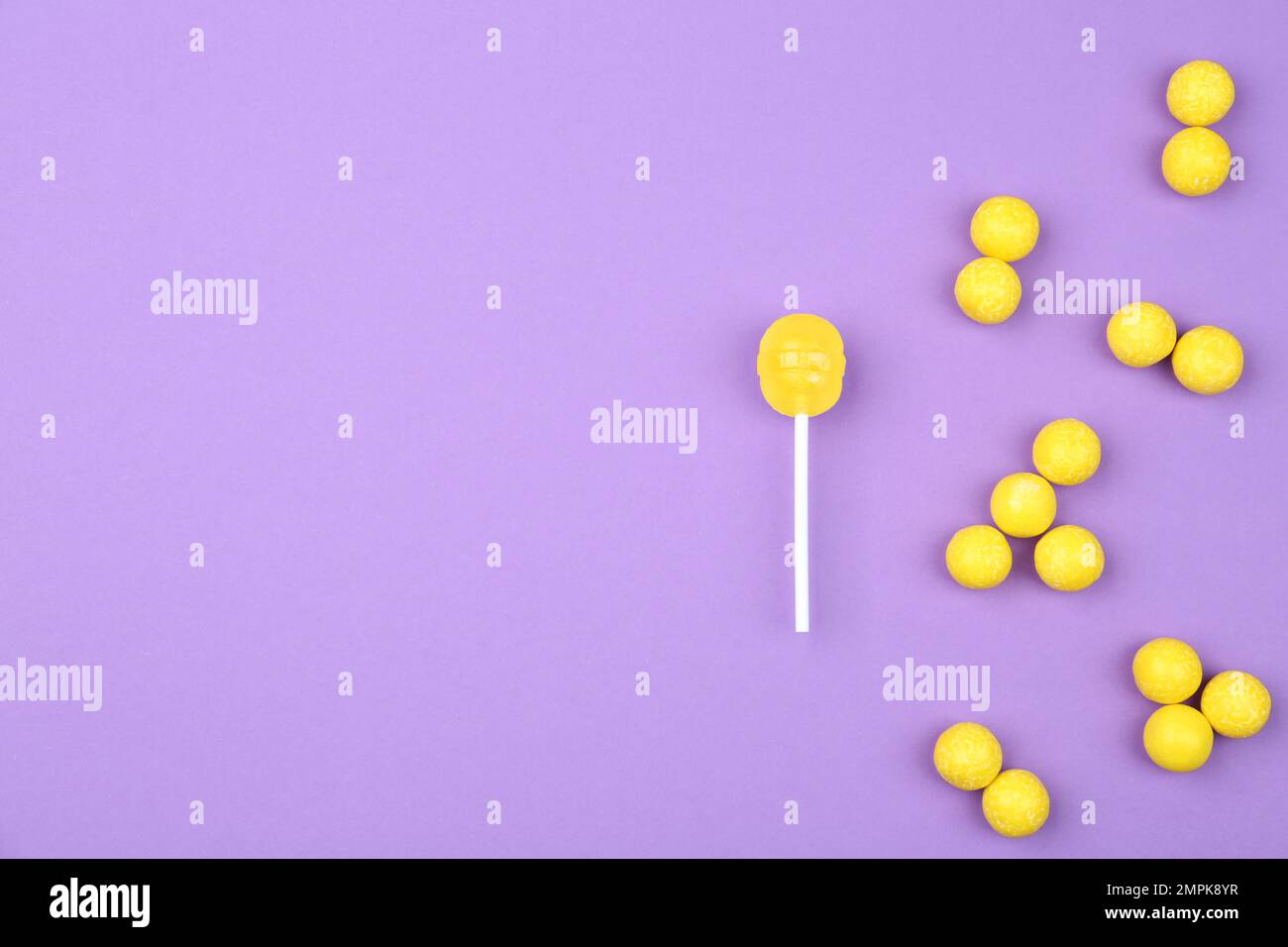 Different lemon candies on purple background, top view. Space for text ...